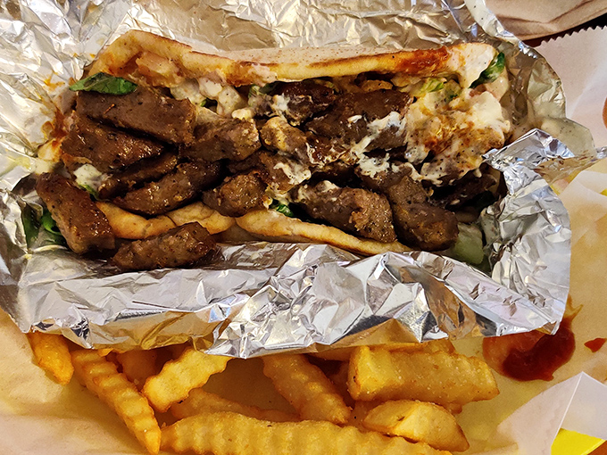 Wrapped in foil like a precious gift, this gyro delivers street food perfection with seasoned meat, fresh veggies, and those addictively crispy fries on the side.