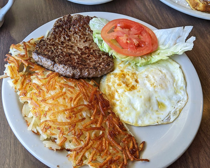 The holy trinity of breakfast: perfectly seared hamburger steak, sunny-side-up eggs, and hash browns that achieve the golden-brown perfection we all aspire to in life.