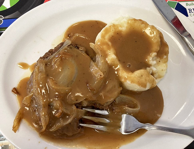 Hamburger steak swimming in savory gravy alongside creamy mashed potatoes &ndash; comfort food that speaks the universal language of "everything's gonna be alright."
