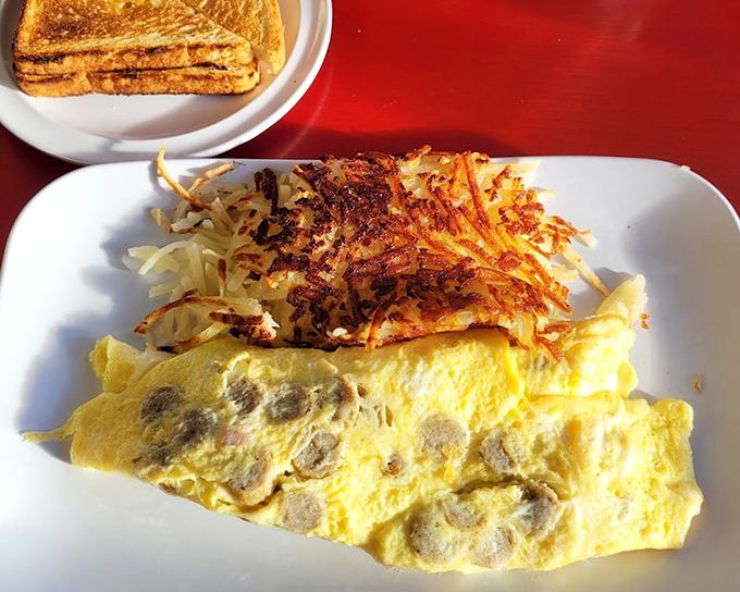 Breakfast alchemy at its finest: a golden omelet studded with savory morsels, paired with hash browns so crispy they practically sing.