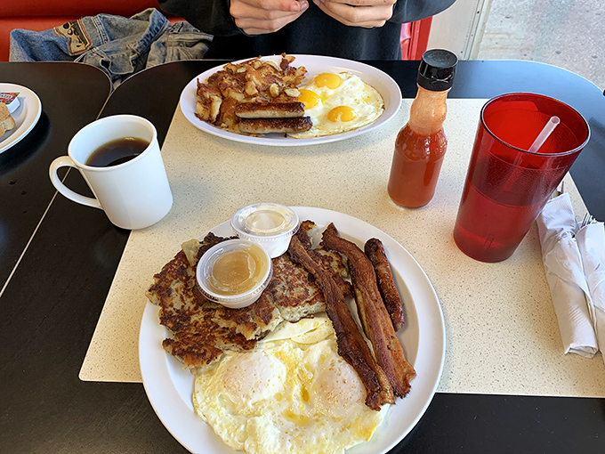 Breakfast perfection on a plate: crispy hash browns, eggs with that ideal runny yolk, and bacon that would make vegetarians question their life choices.