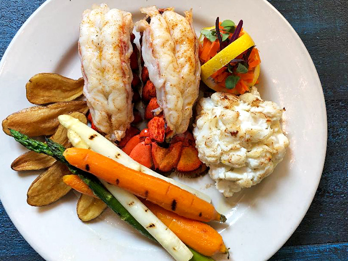 Twin lobster tails lounging on a plate like they're at a spa retreat, surrounded by colorful vegetables that know they're just the supporting cast. 