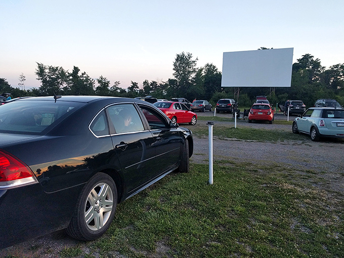The classic movie screen stands tall against the twilight sky, a canvas awaiting stories while cars gather like modern-day campfires.