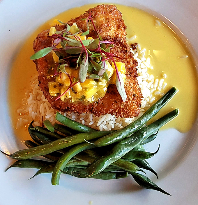 Macadamia-crusted halibut perched atop rice like culinary royalty, surrounded by green beans and bathed in a sauce that whispers, "Take another bite."
