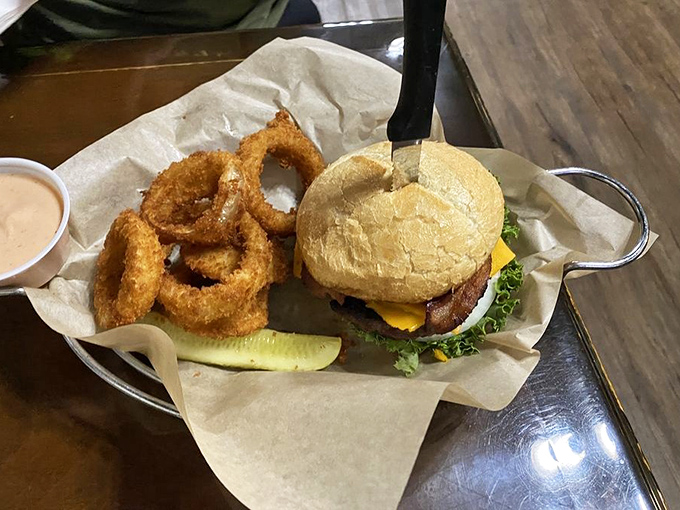 This isn't just a burger—it's architecture. The perfect bun-to-meat ratio with those golden onion rings might make you forget your table manners.