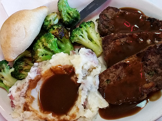 Comfort food royalty: tender meatloaf swimming in rich gravy alongside fluffy mashed potatoes and vibrant broccoli—grandma would approve.