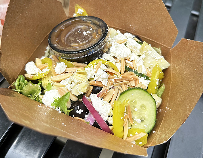 A Mediterranean salad that actually looks like someone cares&mdash;fresh vegetables, feta, and almonds nestled in a compostable container that says "we're trying here."