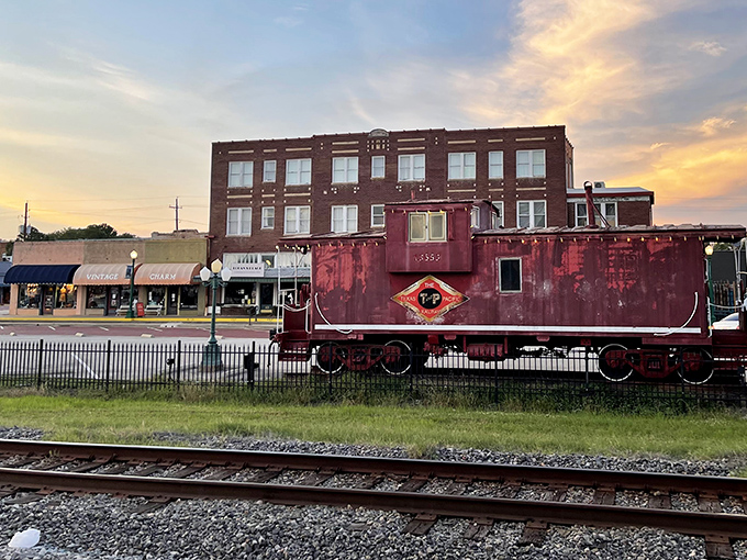 The vintage Texas & Pacific caboose guards downtown Mineola like a crimson sentinel, a permanent reminder of the railroad heritage that birthed this charming town.