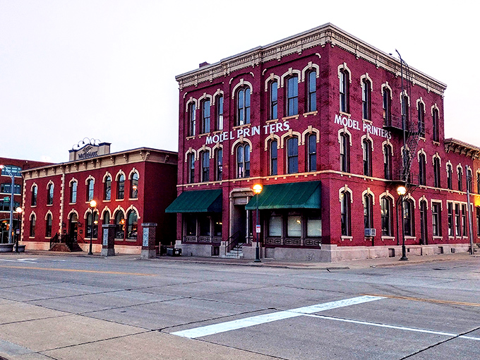 The Model Printers building stands as a crimson testament to Moline's industrial heritage, its brick fa&ccedil;ade weathered by a century of Midwestern seasons.