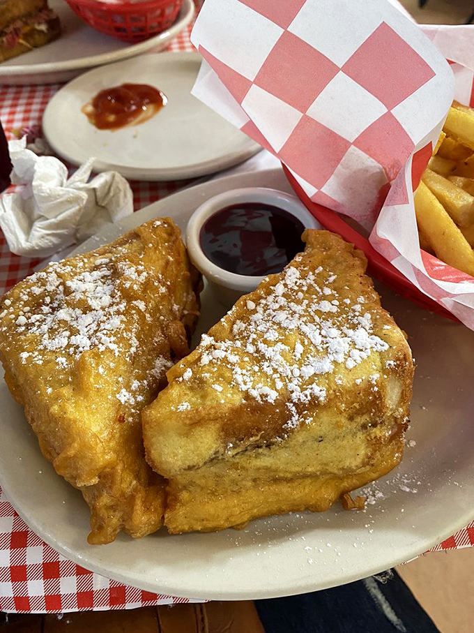 The Monte Cristo sandwich arrives dusted with powdered sugar like fresh snow on a mountain of ham and cheese. Sweet meets savory in perfect harmony.