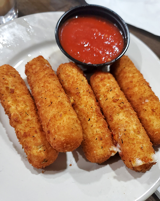 Golden-brown mozzarella sticks &ndash; the universal language of "yes, you deserve this" &ndash; stand at attention beside their marinara companion.