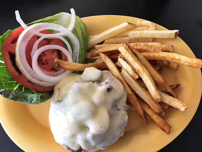 A burger that requires both hands and a strategy. The melted cheese cascading down the sides is performing what can only be described as a dairy waterfall.