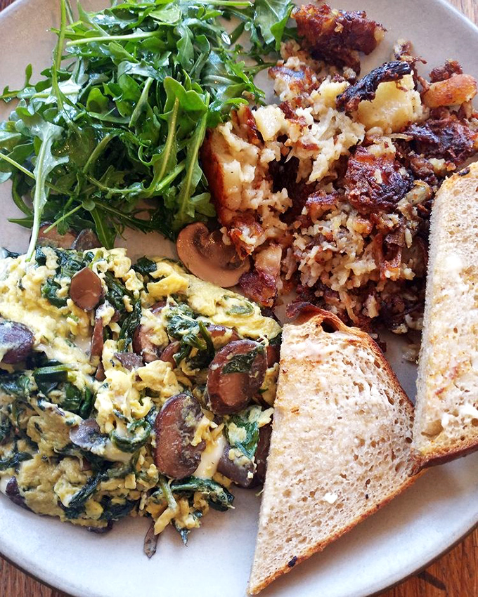 When scrambled eggs meet mushrooms and greens, magic happens on a plate with toast standing guard.