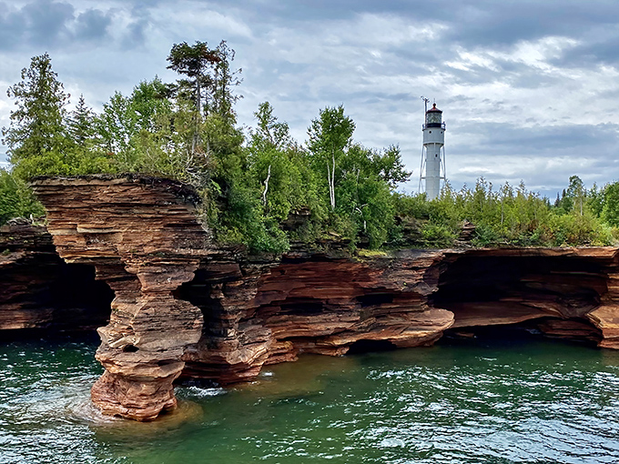 Nature's sculptural genius on display: Lake Superior's waves have carved these dramatic red sandstone sea caves, with a lighthouse standing sentinel nearby.