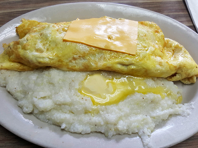 Cheese oozing over a perfectly folded omelet atop a cloud of buttery grits&mdash;proof that simplicity, when done right, is the ultimate sophistication.