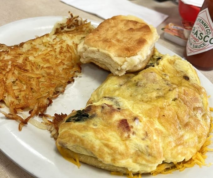 The omelet that launched a thousand satisfied sighs, accompanied by a biscuit so fluffy it practically hovers above the plate.