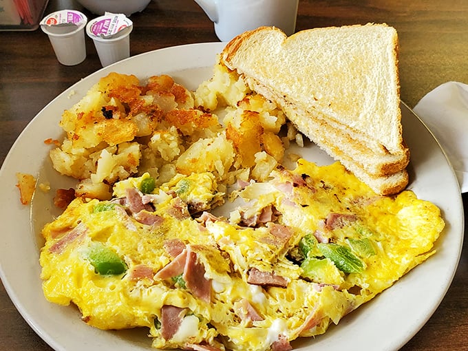 An omelet so generously stuffed it needs structural engineering support, partnered with home fries that earned their diploma.