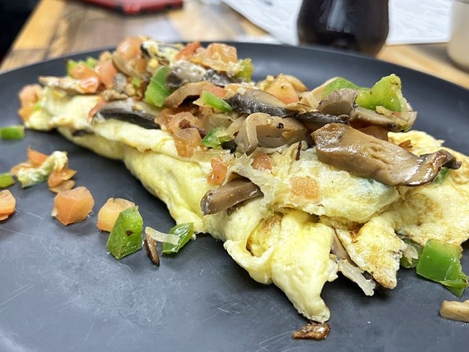 An omelet that doesn't just sit on the plate&mdash;it commands attention with fresh vegetables and perfect execution. Breakfast elevated beyond the ordinary.