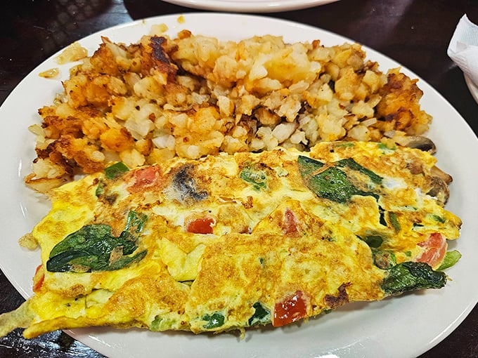 Breakfast perfection: a veggie-packed omelet alongside home fries that somehow manage to be both crispy and tender simultaneously.