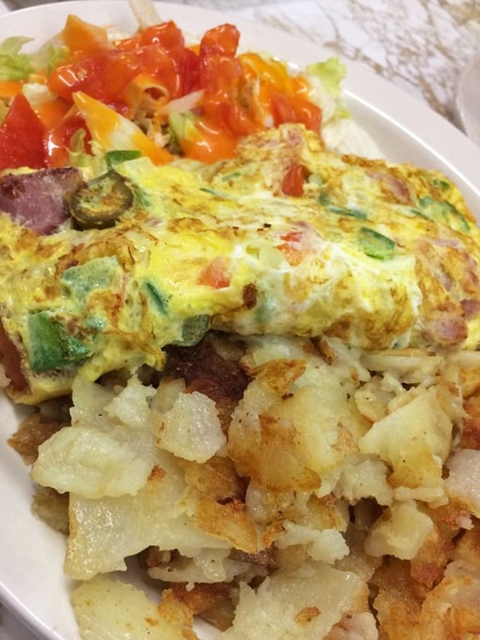 Breakfast alchemy at its finest&mdash;an omelet packed with veggies and meat, alongside potatoes crisped to golden perfection on a well-seasoned grill.