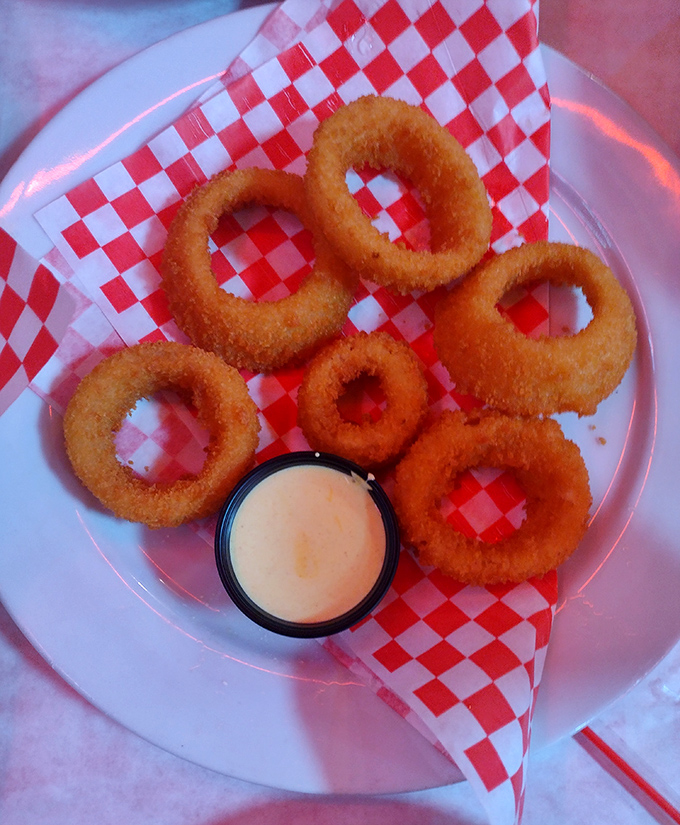 Golden-fried onion rings that crunch like autumn leaves, with dipping sauce that makes you wonder why salads even exist.