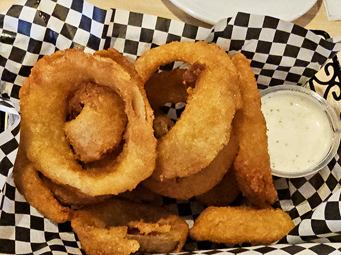 Golden, crispy onion rings that shatter with each bite, served in a checkered basket that screams "trust me, I know comfort food."