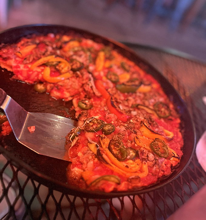 A symphony of colors and textures: sausage, peppers, and olives dance across a canvas of vibrant sauce in this pan-style masterpiece.