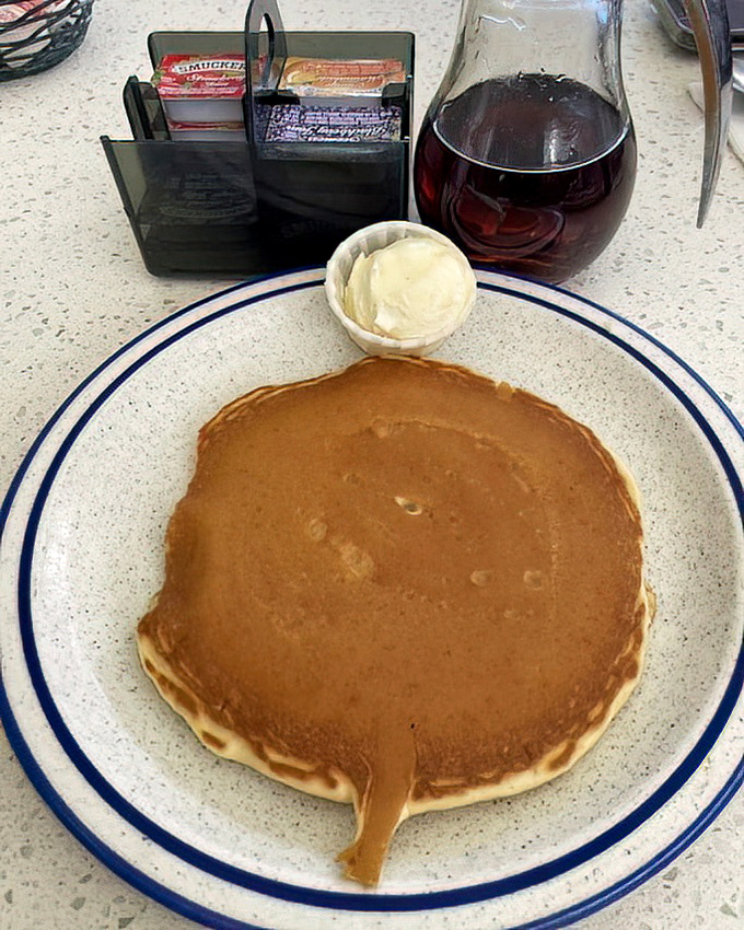 The pancake that launched a thousand road trips. Perfectly golden, slightly bigger than the plate, with butter melting into a maple syrup river.
