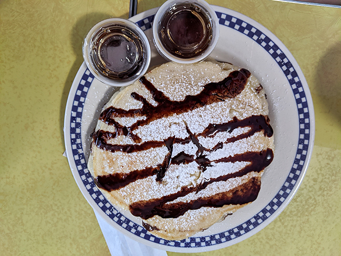 Pancakes drizzled with chocolate sauce and dusted with powdered sugar&mdash;proof that sometimes the universe's greatest pleasures come in simple, circular form.