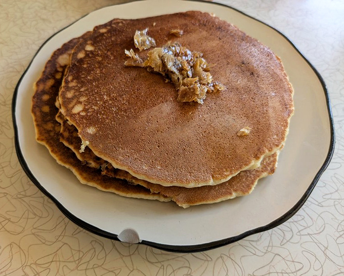These pancakes aren't just breakfast, they're an event—golden-brown canvases waiting for the artistic drizzle of maple syrup from above.