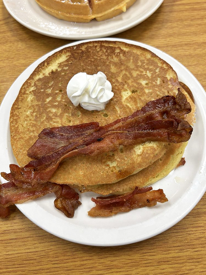 Fluffy pancakes so light they practically float off the plate, accompanied by perfectly crispy bacon strips.