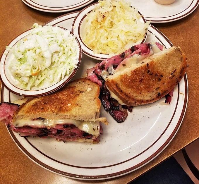 The Reuben: an architectural marvel of grilled rye, melted Swiss, tangy sauerkraut, and pastrami stacked so high you'll need to unhinge your jaw like a python.
