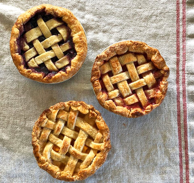 Lattice-topped fruit pies that look like they jumped straight out of a Norman Rockwell painting, each one a perfect circle of handcrafted deliciousness.