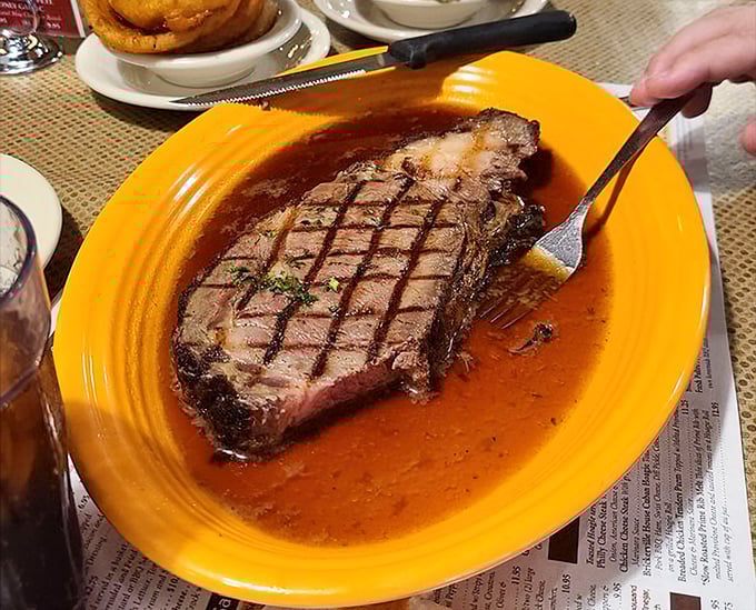 Prime rib swimming in au jus on a sunshine-yellow plate. The grill marks aren't just decoration—they're a promise kept with each tender bite.