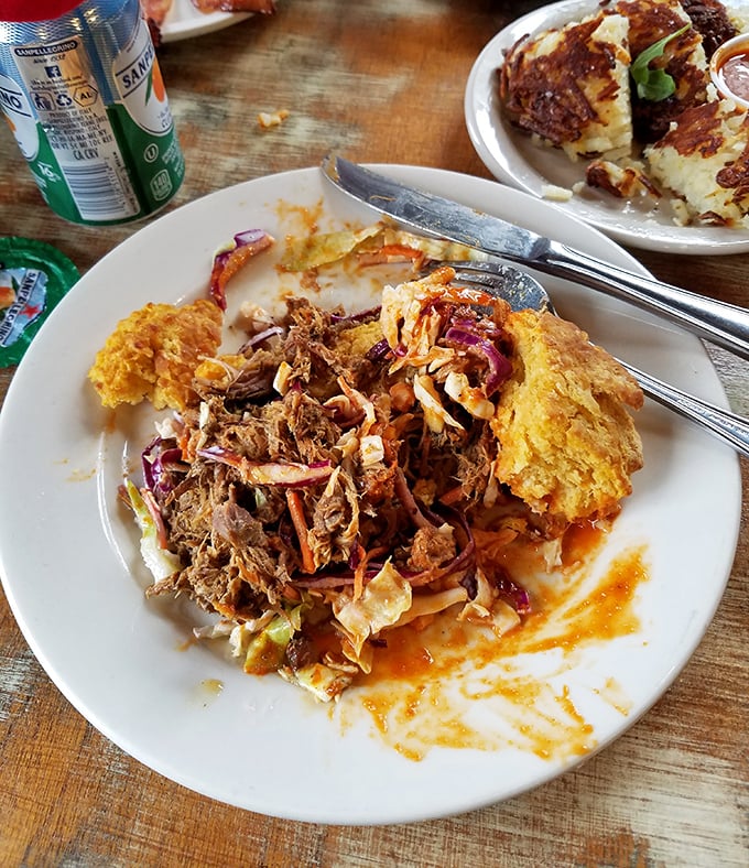Pulled pork nestled between orange-tinted biscuit halves creates a symphony of textures. The sauce dripping down the sides isn't messy&mdash;it's a promise.