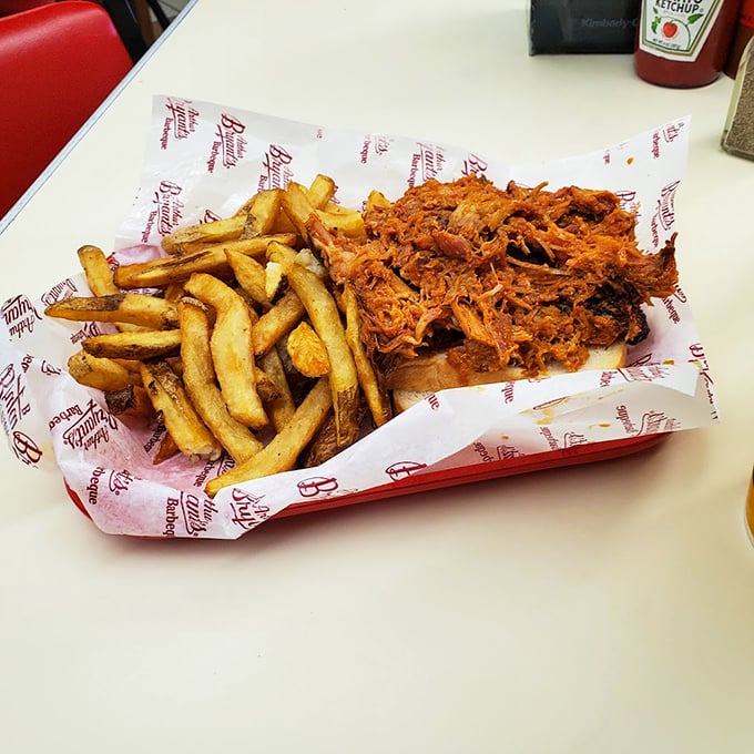 The pulled pork sandwich: where tender strands of smoky heaven meet crispy fries in a paper-lined basket of pure Americana.