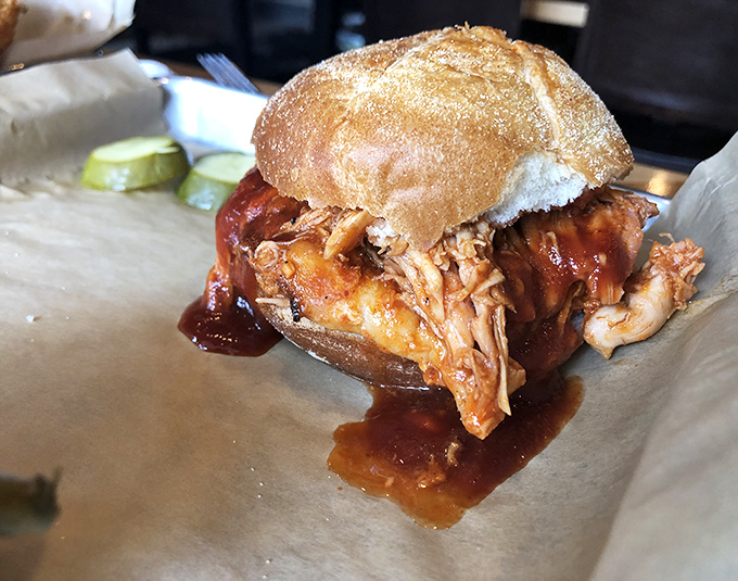 Meet the pulled pork sandwich that launched a thousand road trips. Tender, saucy perfection nestled in a bun that knows its supporting role.