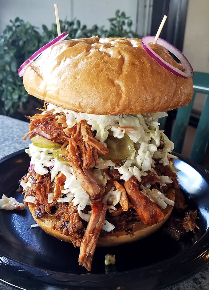 This isn't just a sandwich; it's an architectural marvel of pulled pork, slaw, and pickles that requires both hands and zero shame.