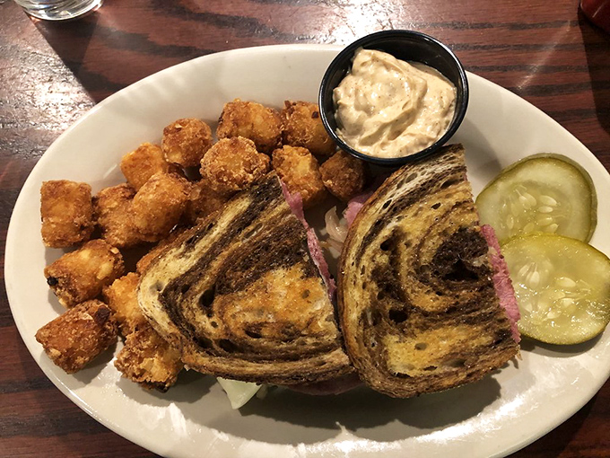 The Reuben sandwich&mdash;where marble rye meets its destiny. Served with crispy tots and pickles that add the perfect tangy counterpoint.
