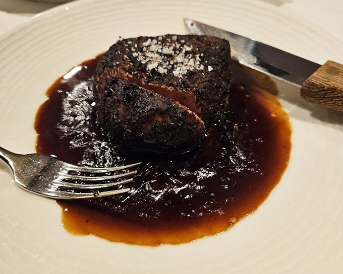 A perfectly seared ribeye swimming in rich sauce – the kind of steak that makes vegetarians question their life choices just from the aroma alone.