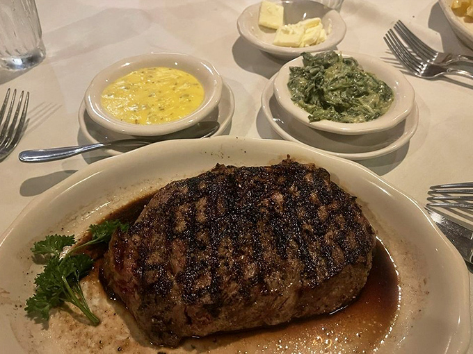 A ribeye with perfect grill marks resting in its own savory juices. The spinach and corn side dishes know they're just supporting actors here.