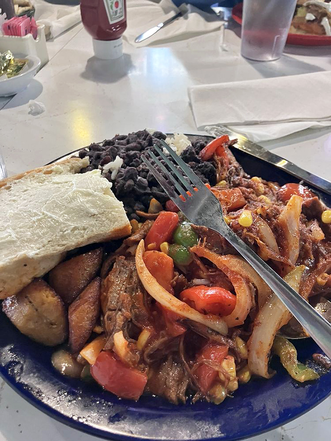 A fiesta on a plate! Tender seasoned meat mingles with colorful peppers, onions and corn, while black beans and Cuban bread stand ready for the party.