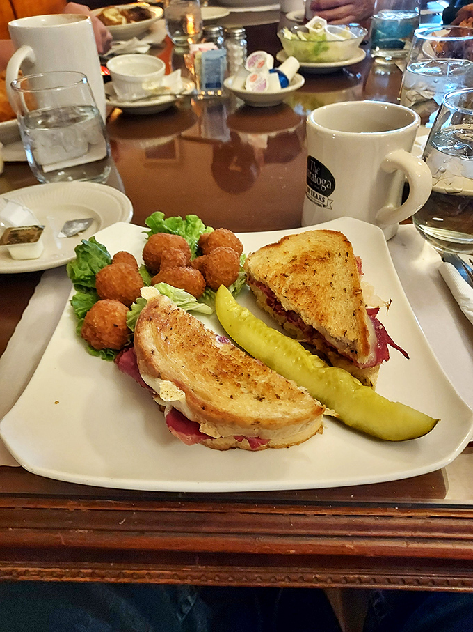 A sandwich so perfectly constructed it deserves architectural recognition, complete with a pickle spear standing guard like a delicious sentinel.