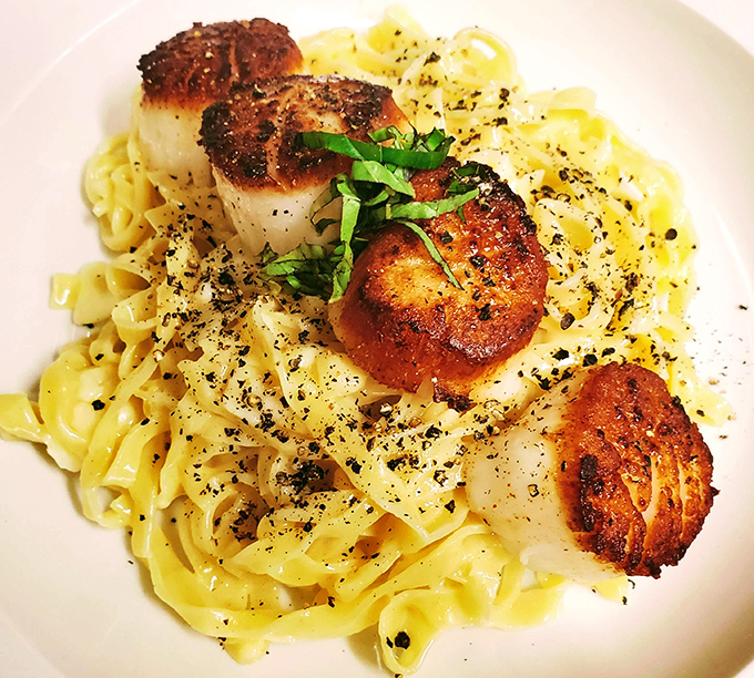 Perfectly seared scallops perched atop buttery pasta &ndash; the kind of dish that makes conversation stop and eyes close in culinary bliss.