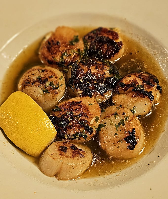 These seared scallops swimming in buttery broth aren't just seafood; they're little ocean medallions of perfection with a golden-brown passport stamp.