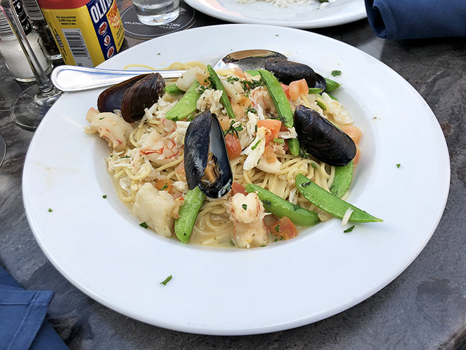 Seafood linguini where mussels, shrimp, and vegetables throw the pasta party of your dreams on a pristine white plate.