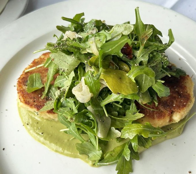 This isn't just a crab cake; it's edible architecture. Golden-crisp exterior gives way to delicate Dungeness crab, all floating on a sea of vibrant green sauce. 