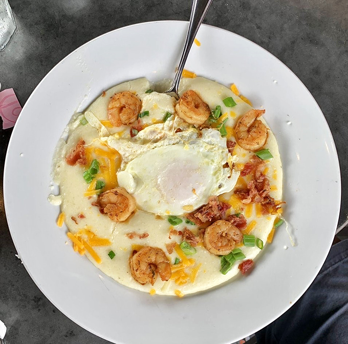 Shrimp and grits elevated to an art form – plump shrimp nestled on creamy cheese grits with bacon, scallions, and a perfectly cooked egg.