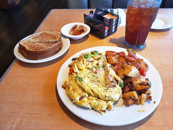An omelet that doesn't just sit on the plate but commands attention, surrounded by home fries that have clearly been taught proper browning techniques.