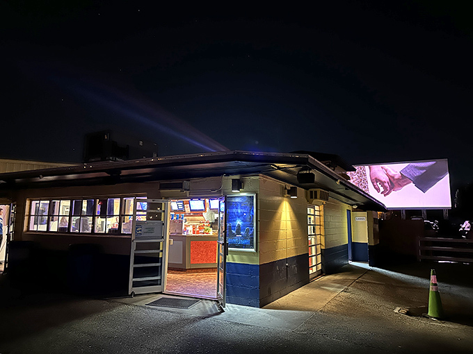 The concession building glows like a beacon in the night, promising buttery popcorn and cold drinks between features.